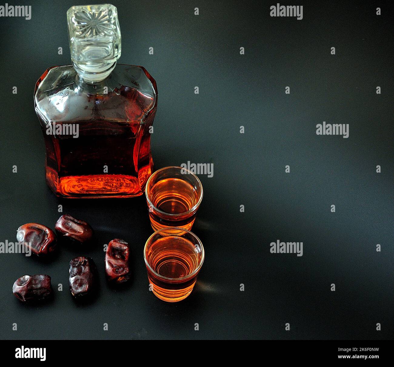 Date liqueur, strong homemade alcohol and dried fruits on a black ...
