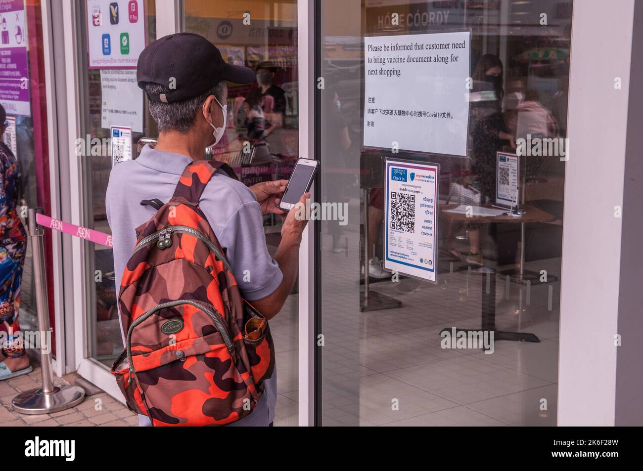 A Cambodian man, in a protective face mask, scans his QR code at the ...