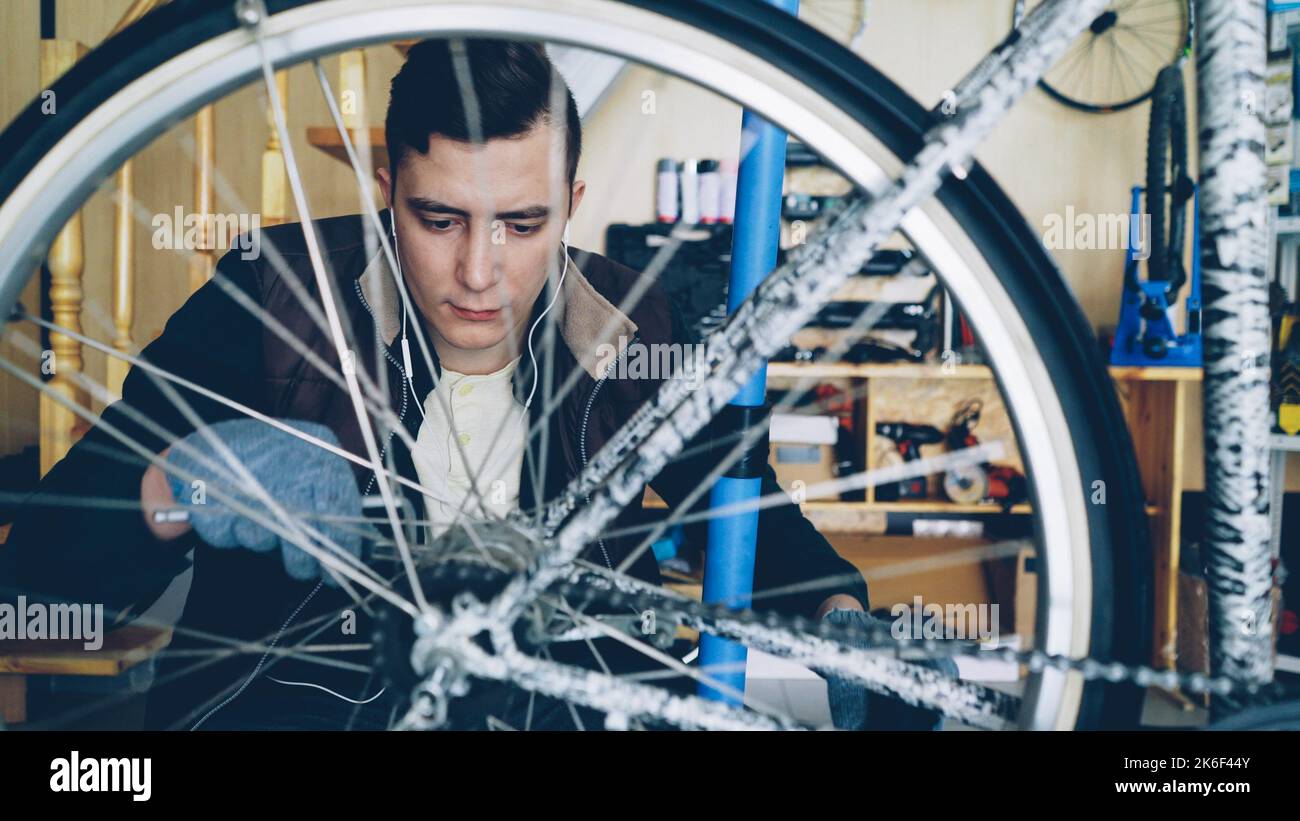 Concentrated handsome guy skilled mechanic is repairing bicycle wheel ...