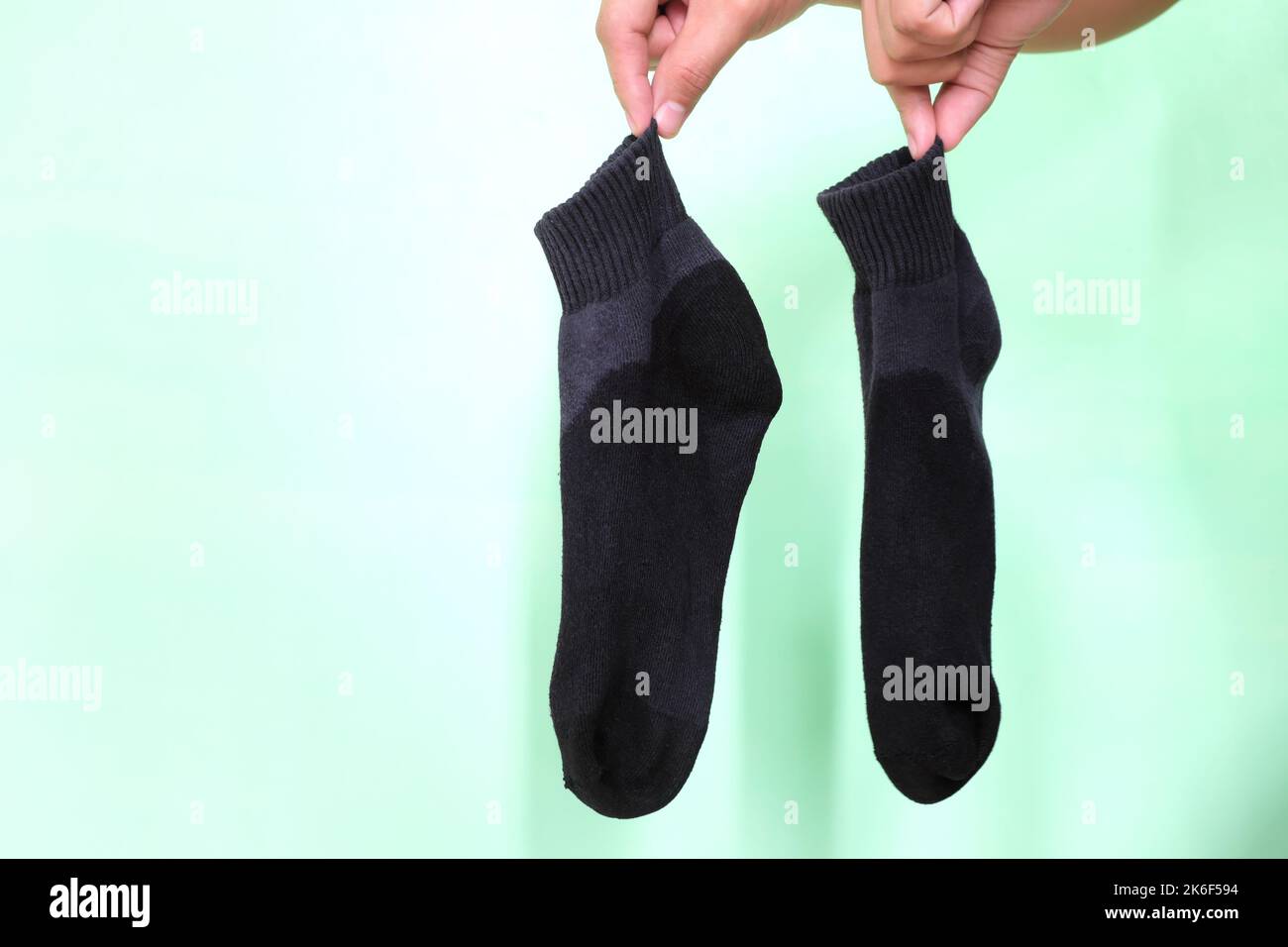 Human hand holding wet, sweaty and stinky socks isolated on green ...
