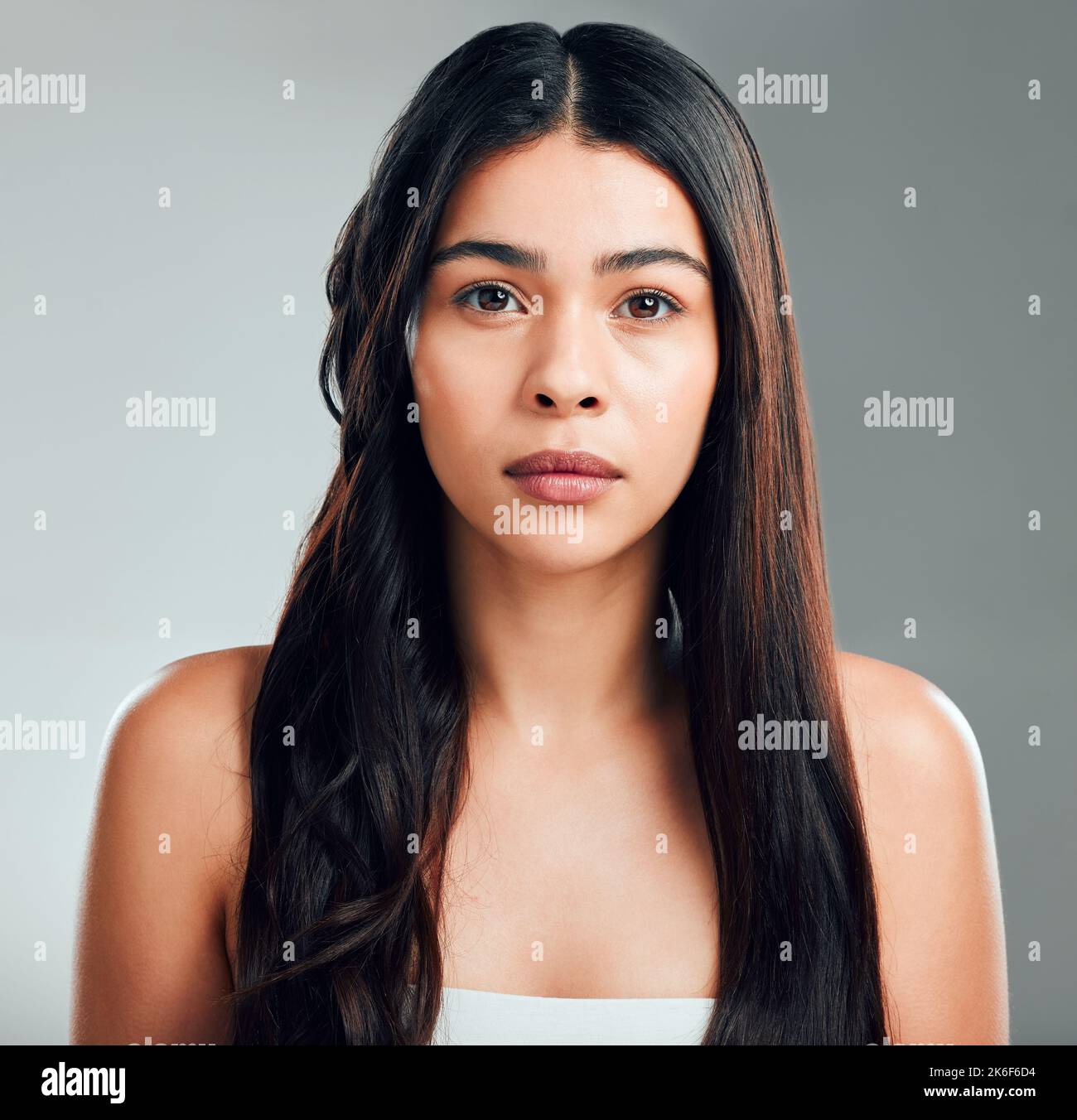 What are you doing to your hair. Studio shot of a beautiful young woman ...
