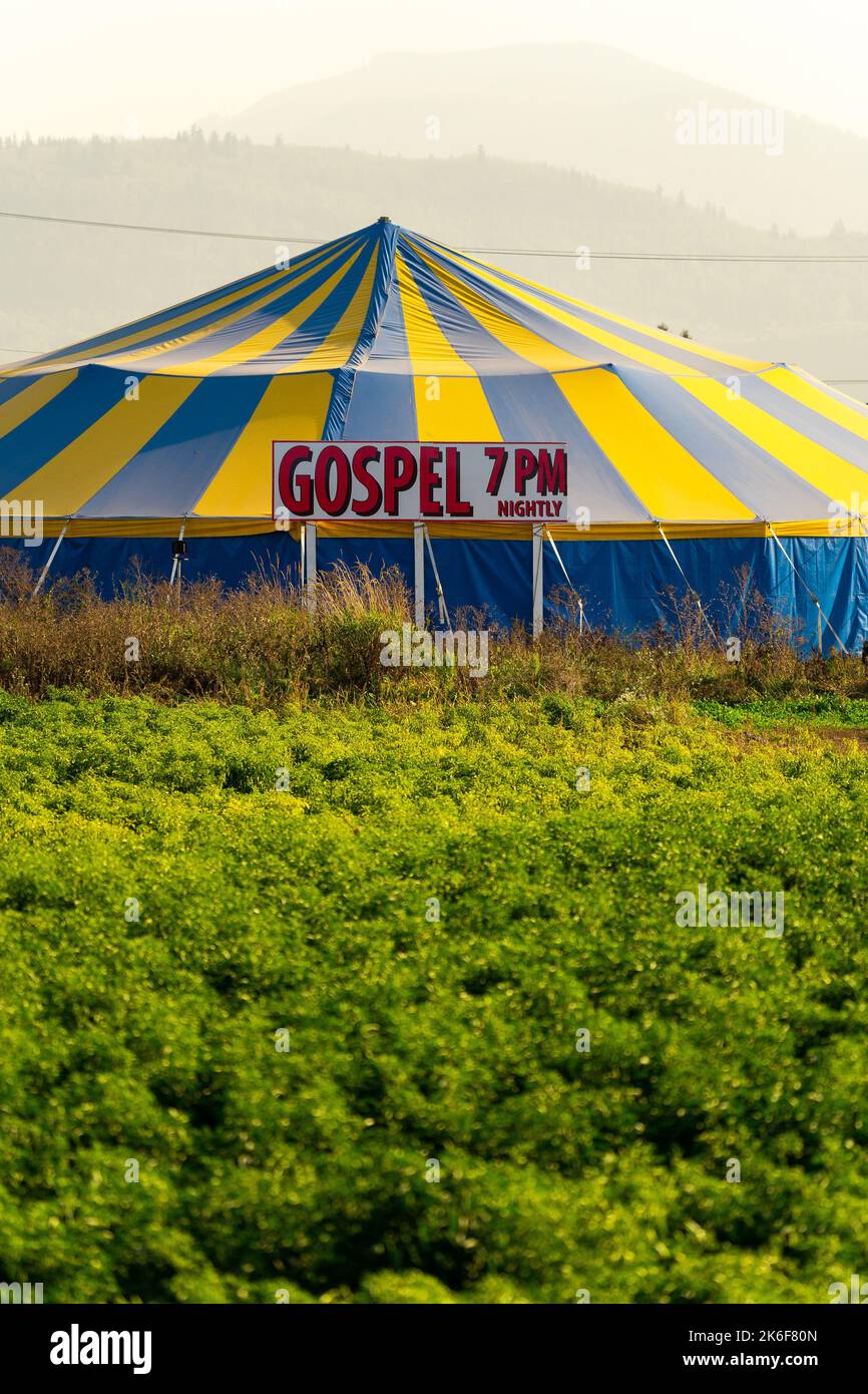 A striped tent erected for nightly Christian gospel services sits in a ...