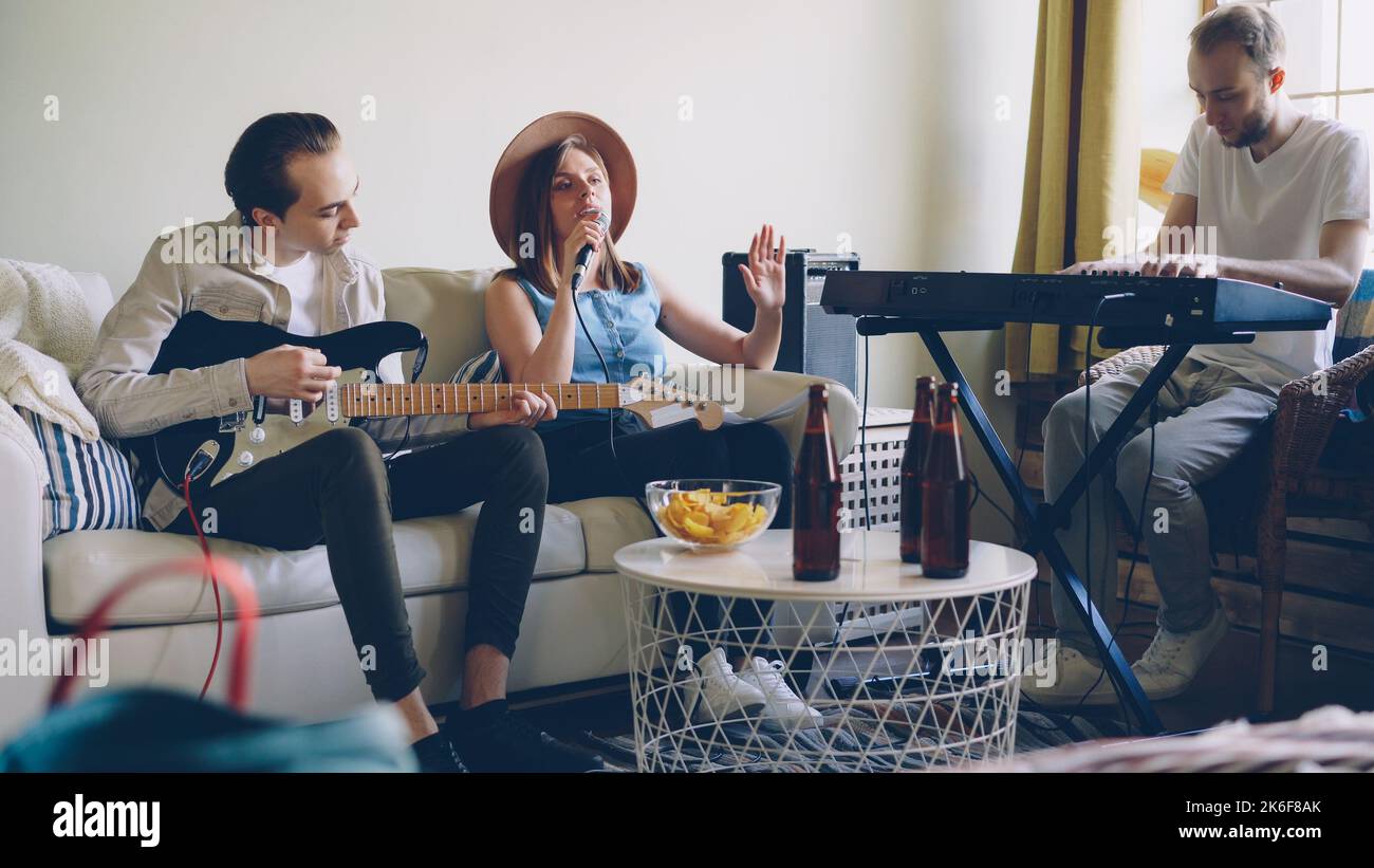 Young friends musicians are practising at home singing and playing ...