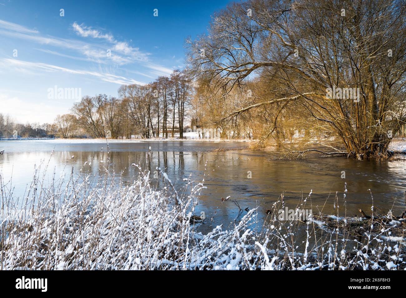 An aerial view of river surrounded by snow covered field and dense ...