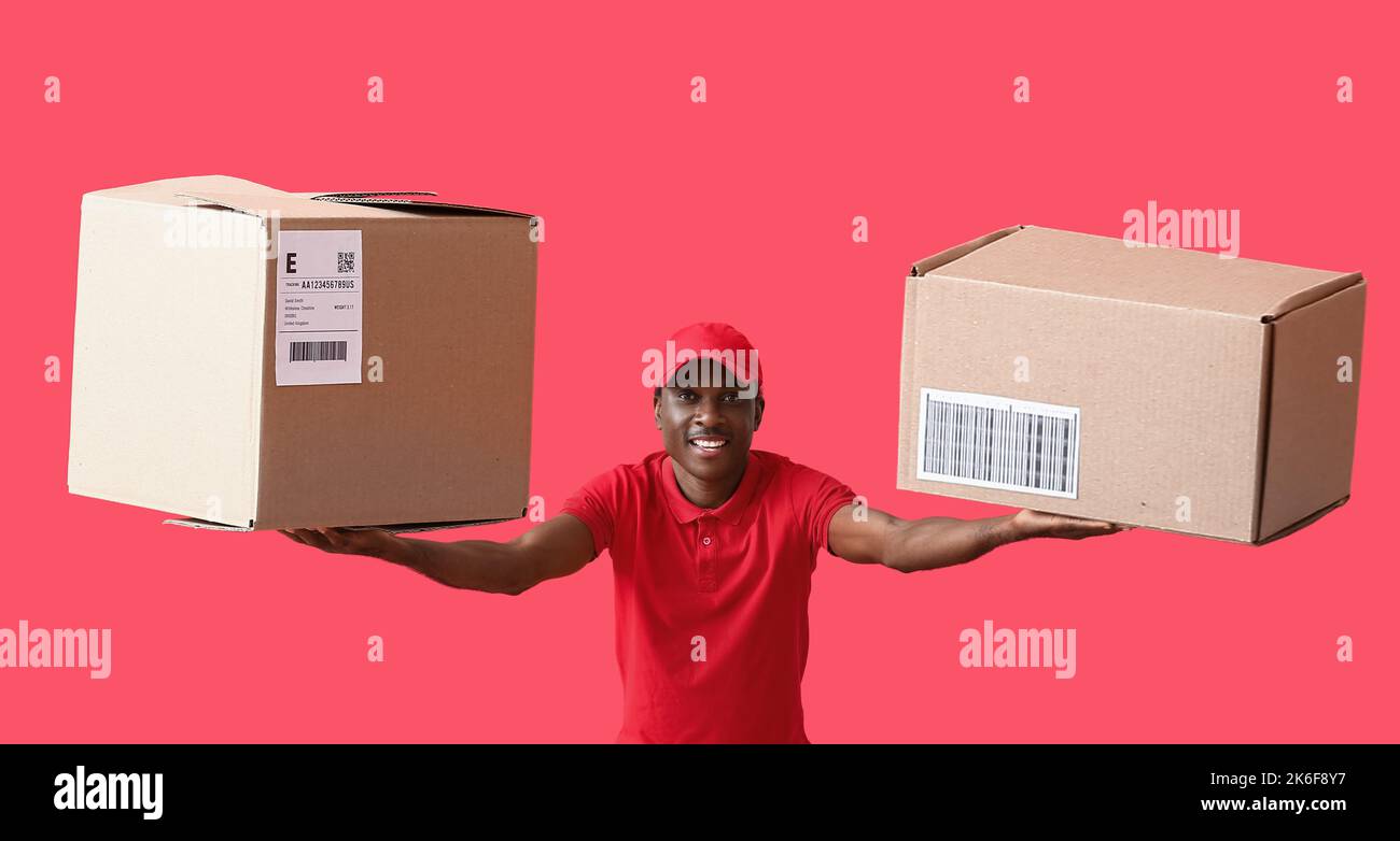 African-American delivery man with big parcels on pink background Stock ...