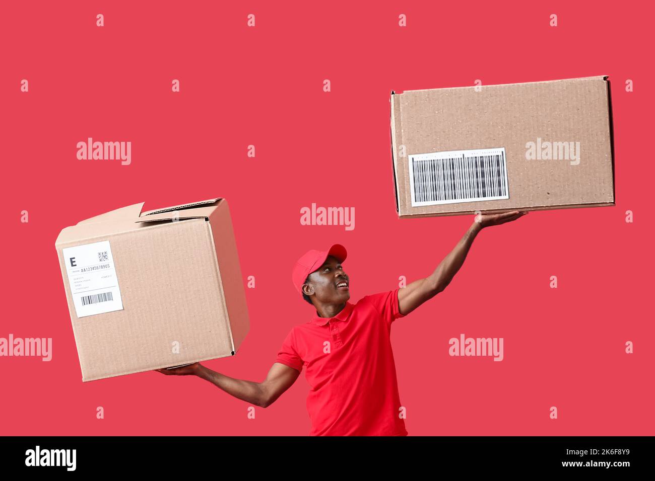 African-American delivery man with big parcels on pink background Stock ...