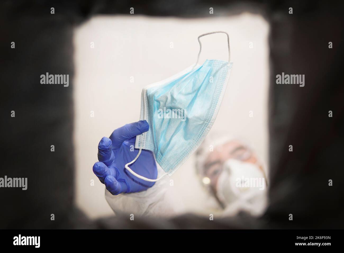 Hand in medical gloves throwing out discarded, used protective masks in ...