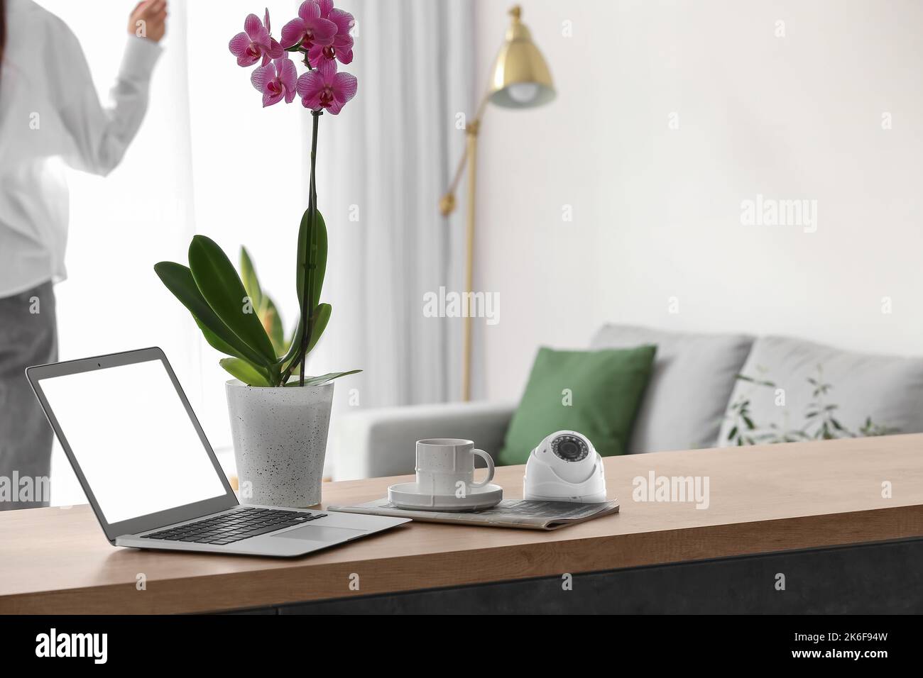 Modern security CCTV camera with laptop, cup of coffee and orchid plant ...