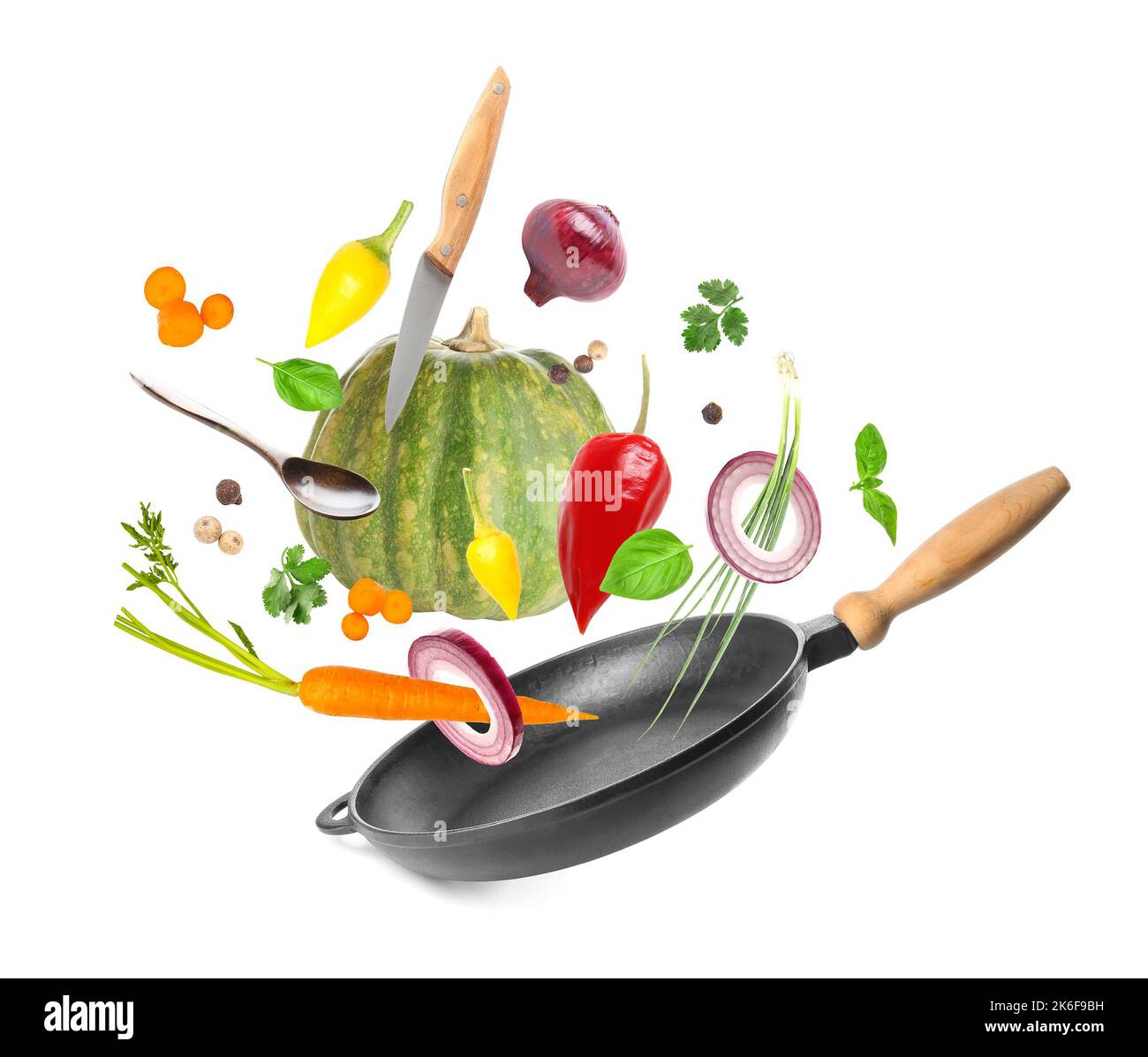 Flying fresh vegetables with utensils and frying pan on white ...