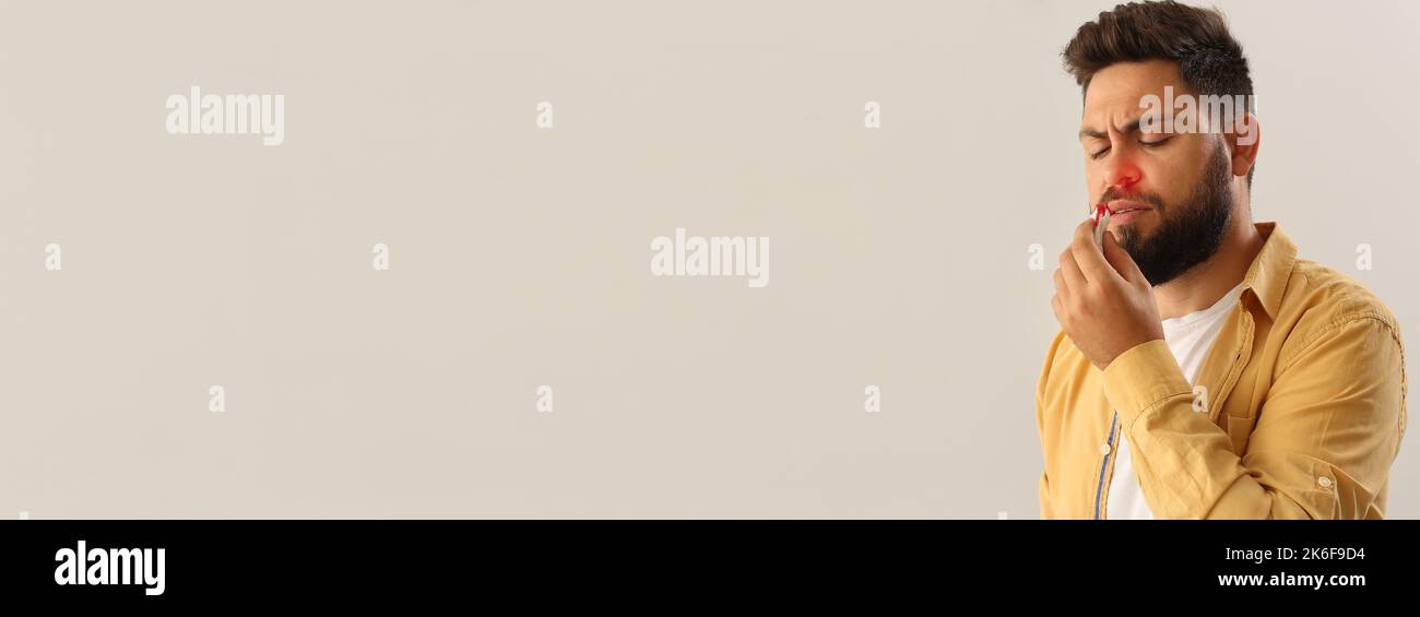 Young man with nosebleed on light background with space for text Stock ...