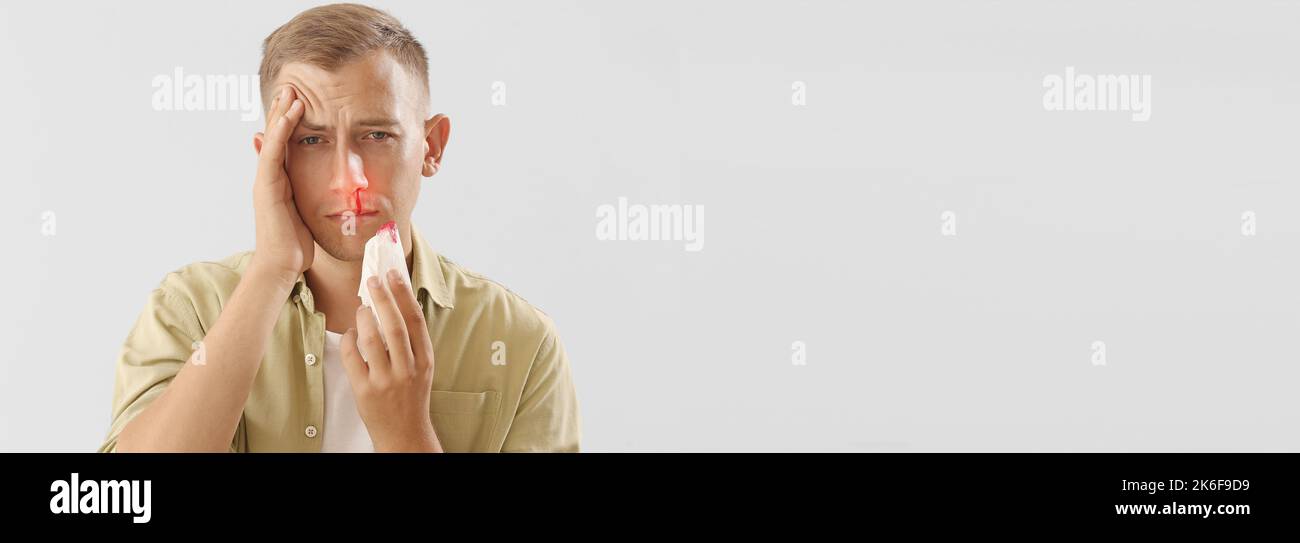Young man with nosebleed on light background with space for text Stock ...