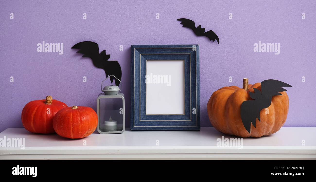 Blank photo frame with Halloween pumpkins, bats and lantern on table ...