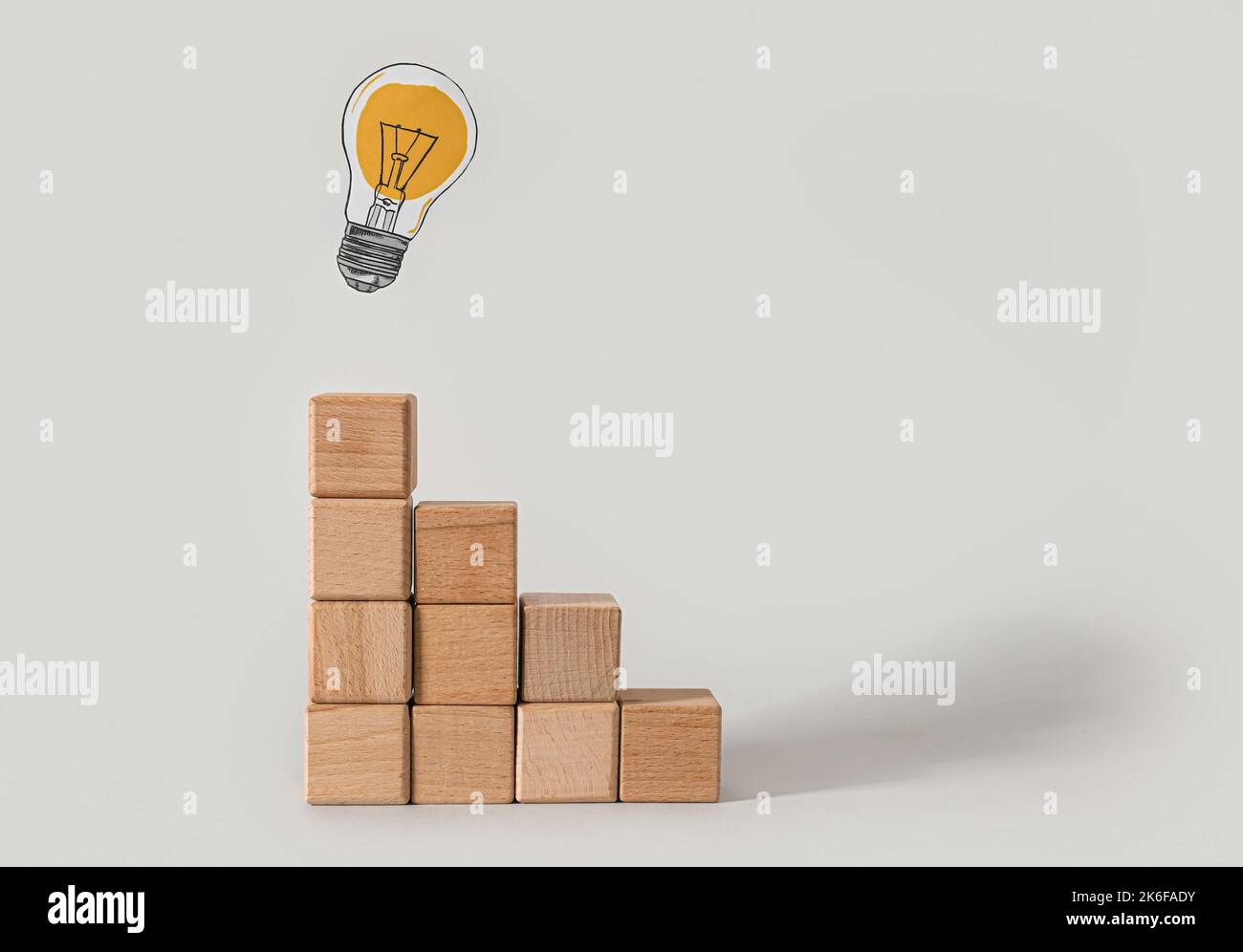 Ladder made of wooden blocks and light bulb on grey background Stock ...