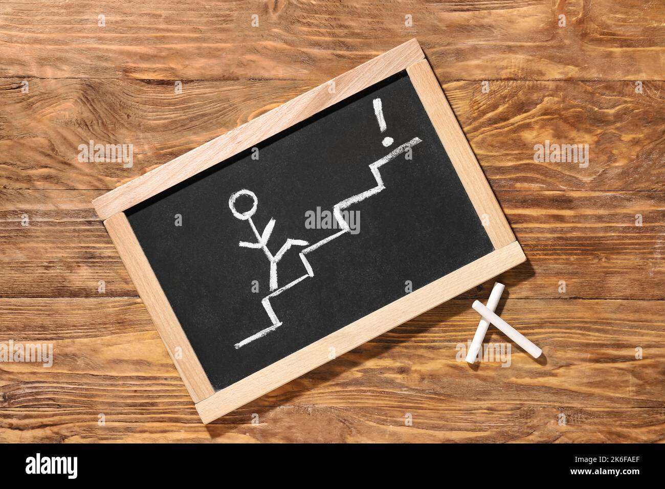 Chalkboard with drawing of person and ladder on wooden background Stock ...