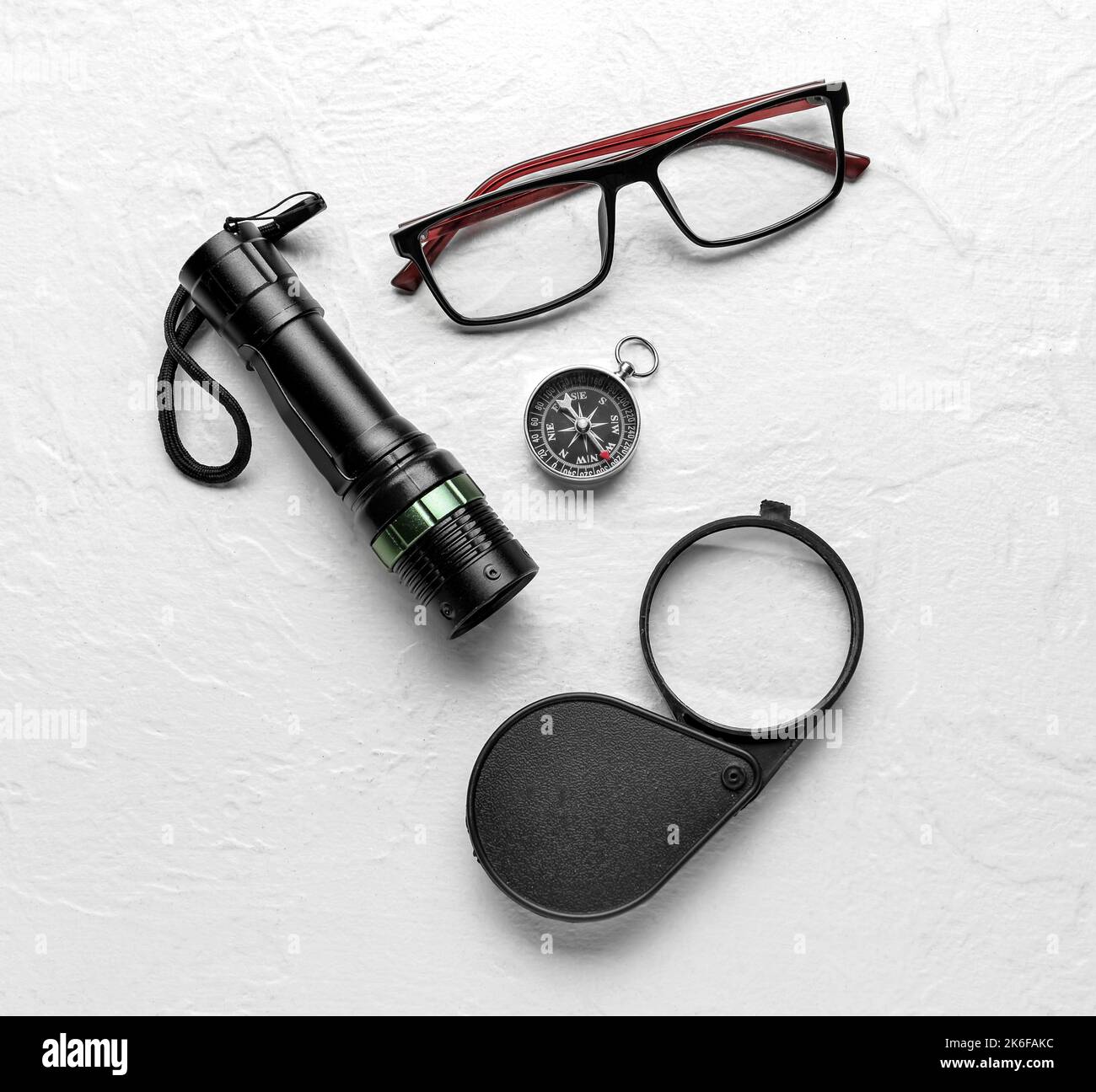 Eyeglasses, compass, magnifier and flashlight on light background Stock ...