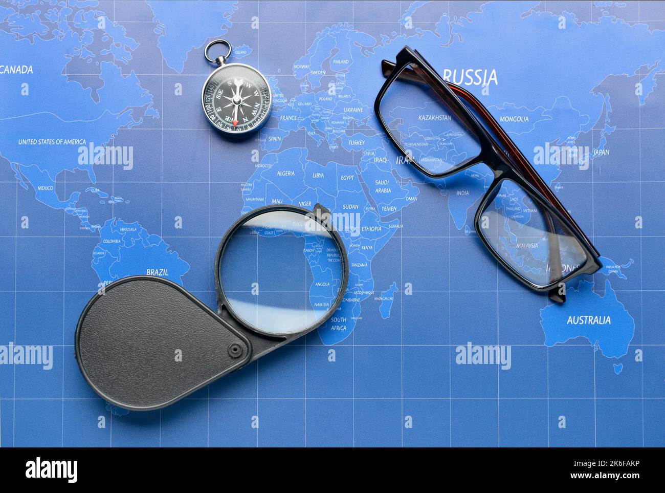 Magnifier, compass and eyeglasses on world map Stock Photo - Alamy