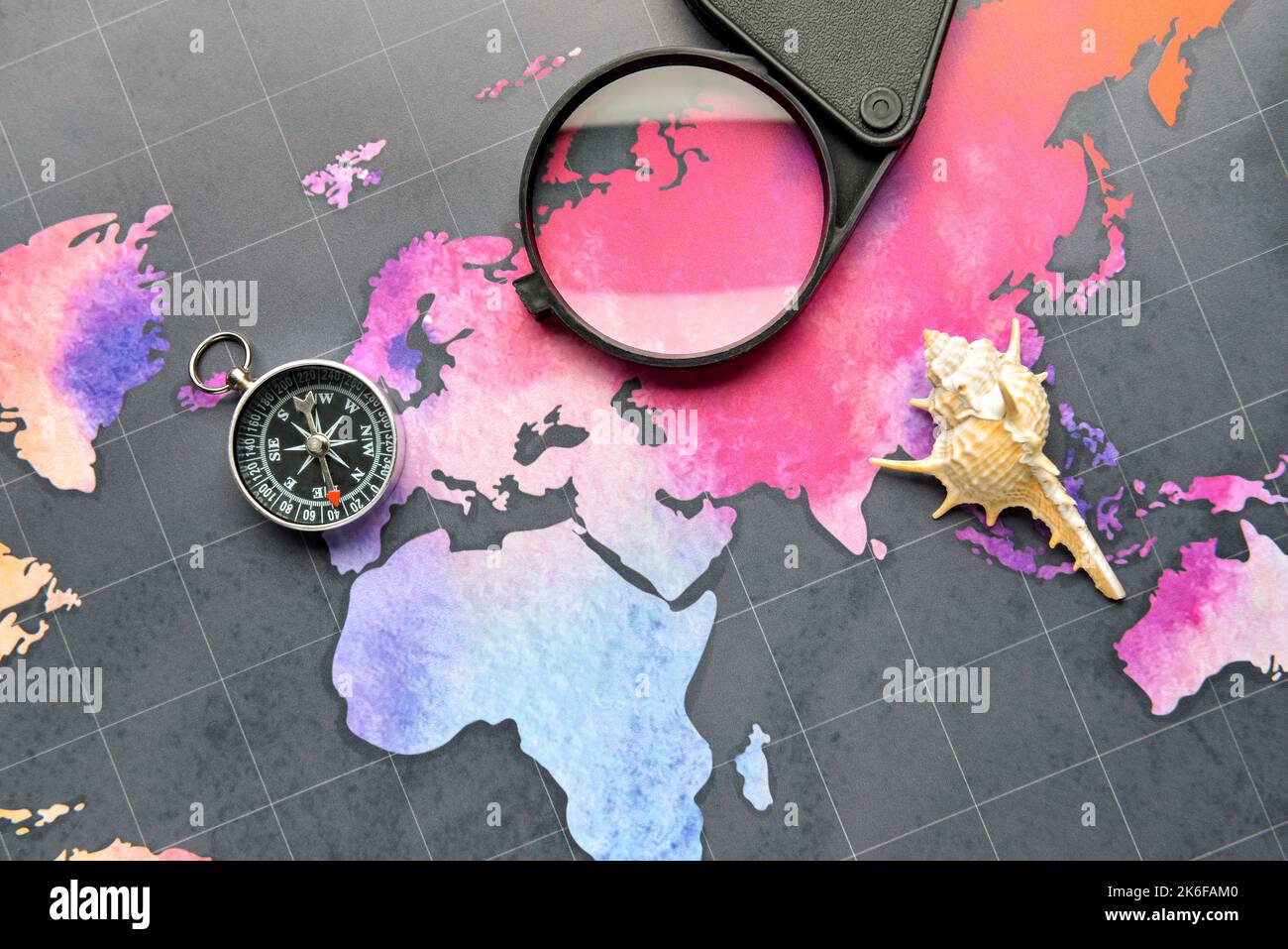 Compass, magnifier and seashell on world map Stock Photo - Alamy
