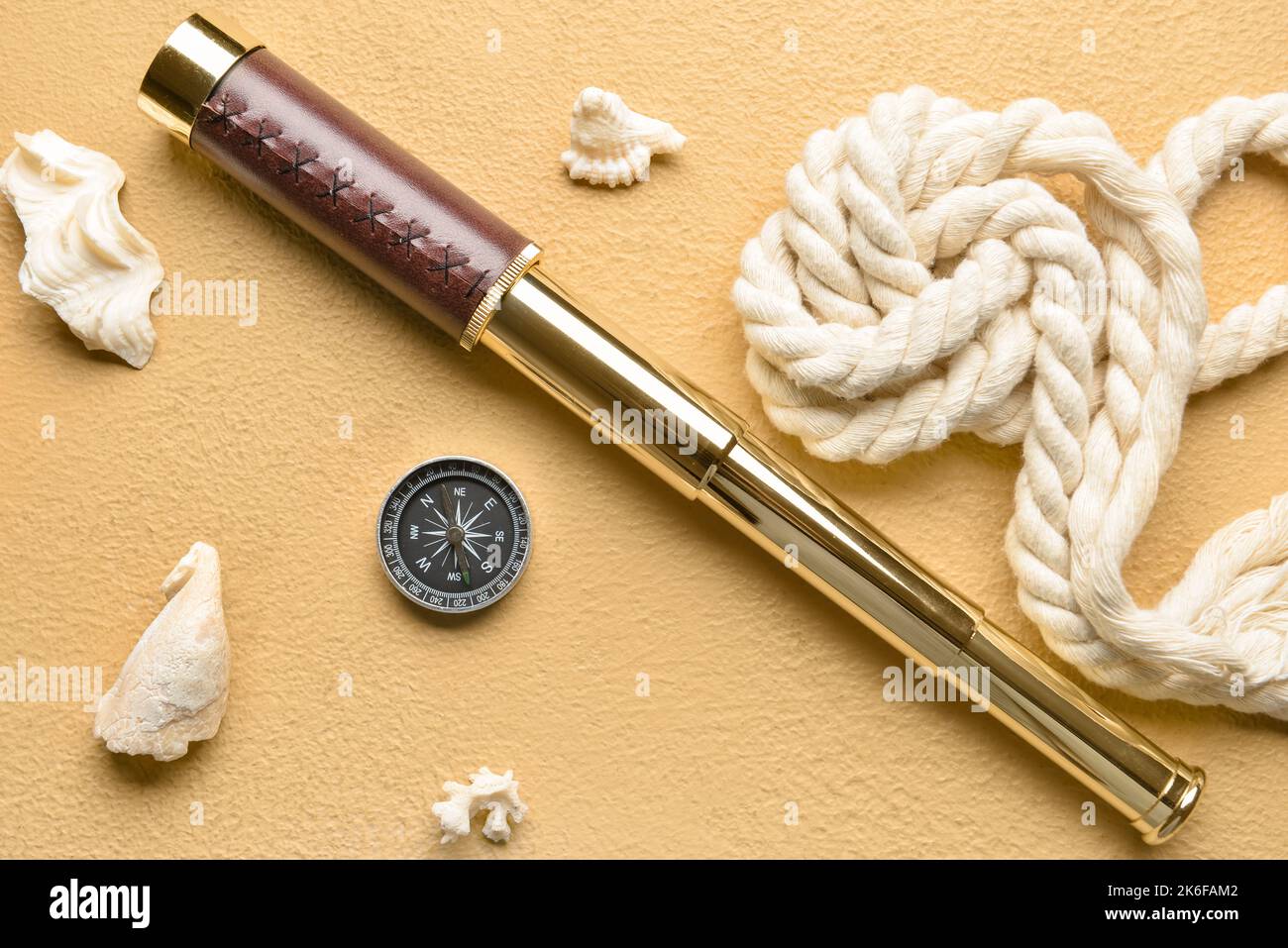 Vintage spyglass, compass, rope and seashells on color background Stock ...