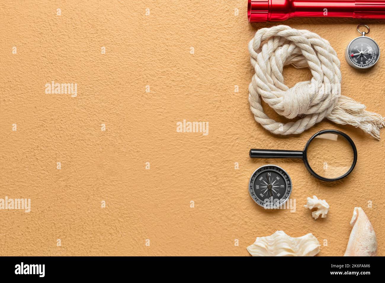 Compasses, magnifier, rope, flashlight and seashells on color ...