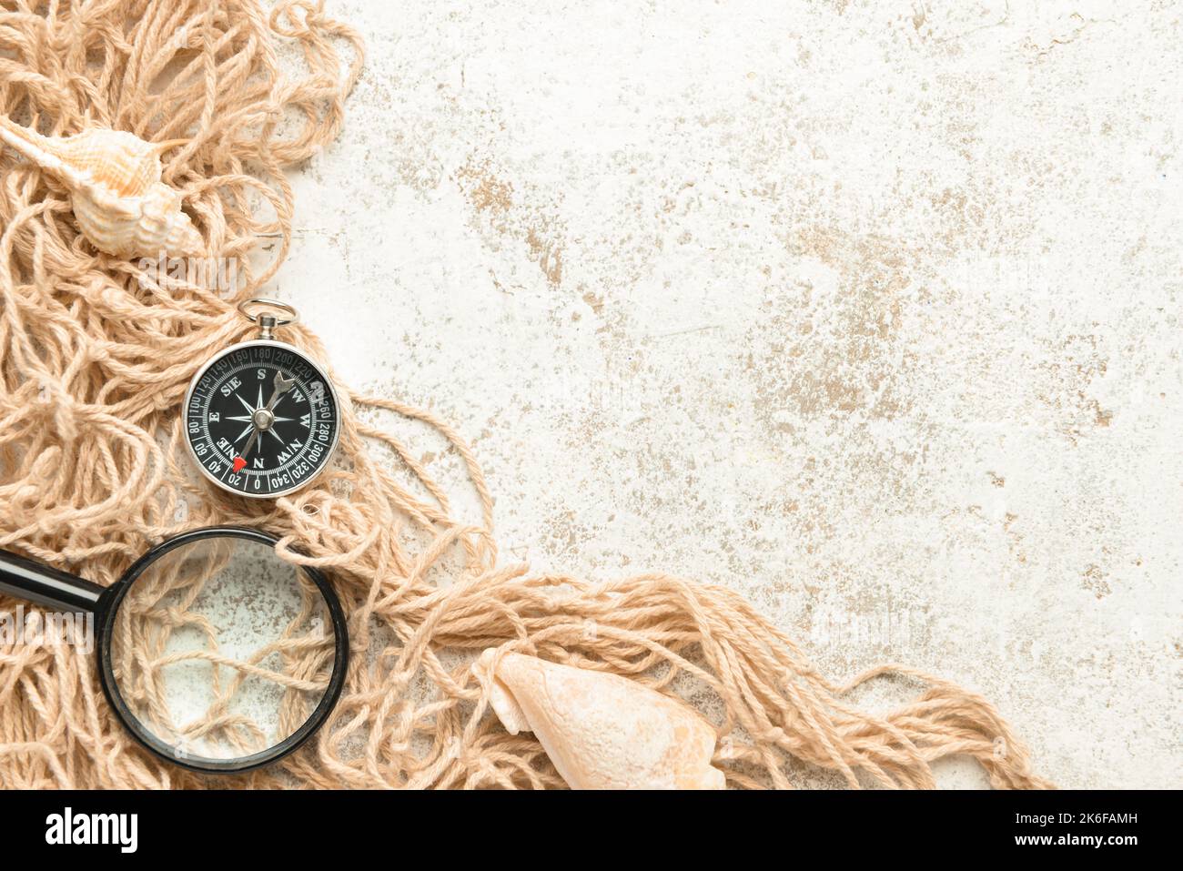 Compass, magnifier, seashell and fishnet on light background Stock ...