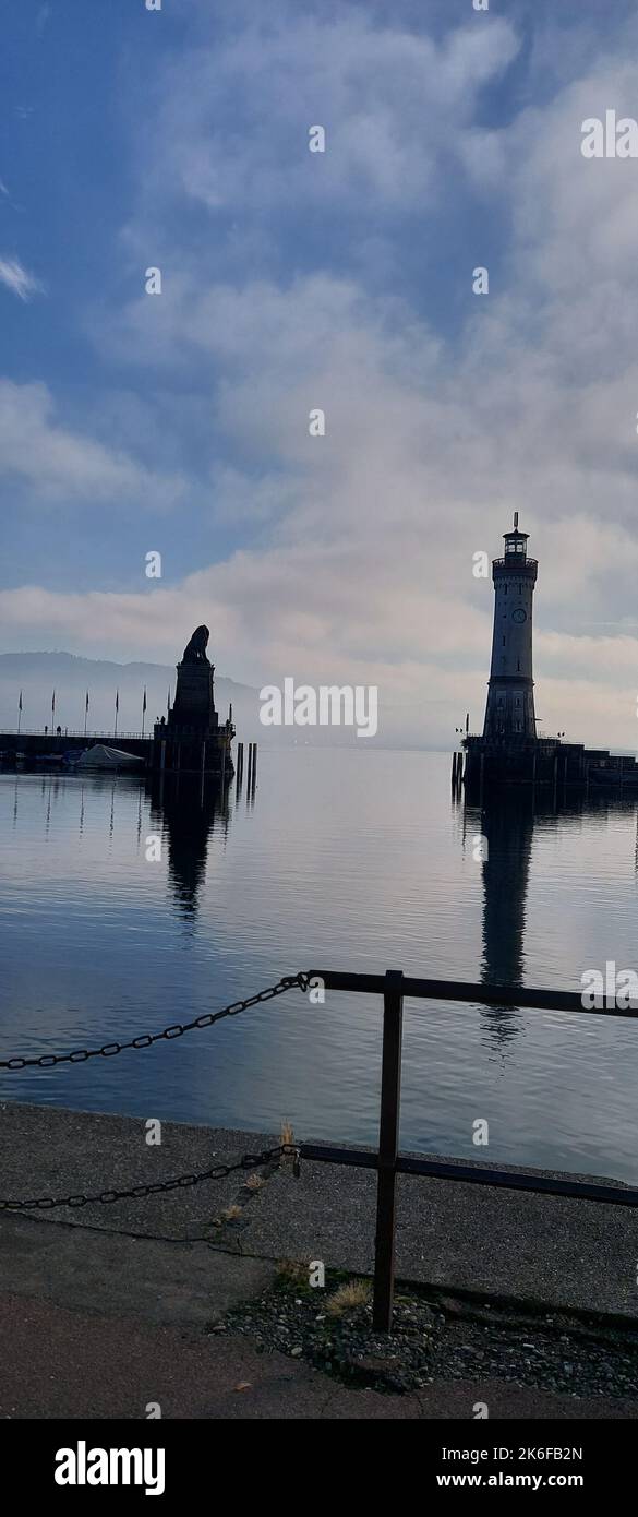 A vertical shot of a lighthouse in the water with visible reflections ...