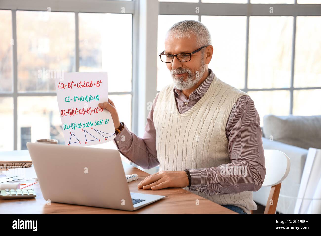 Mature teacher conducting Math lesson online at home Stock Photo - Alamy