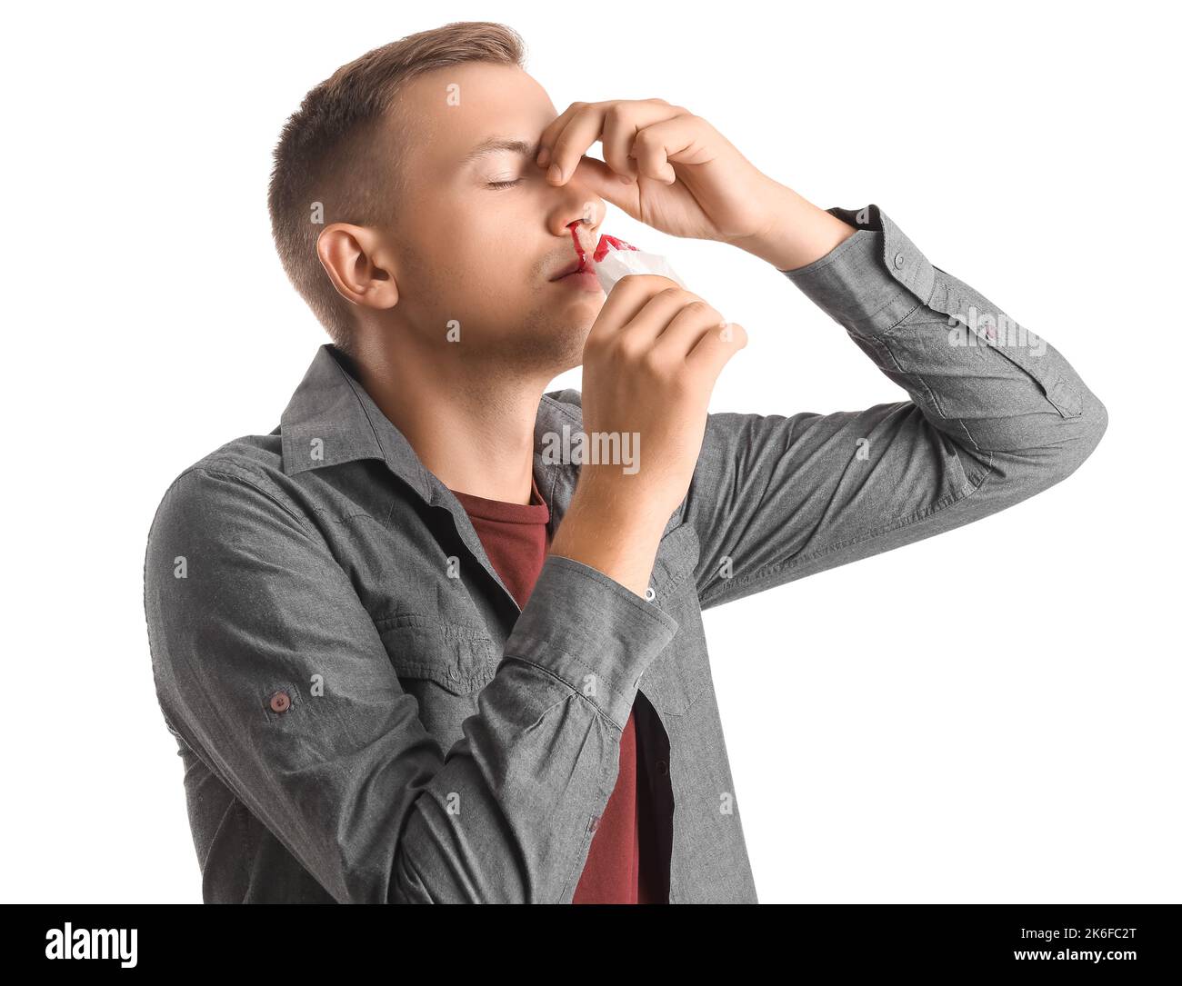 Young man wiping nosebleed with tissue on white background Stock Photo ...