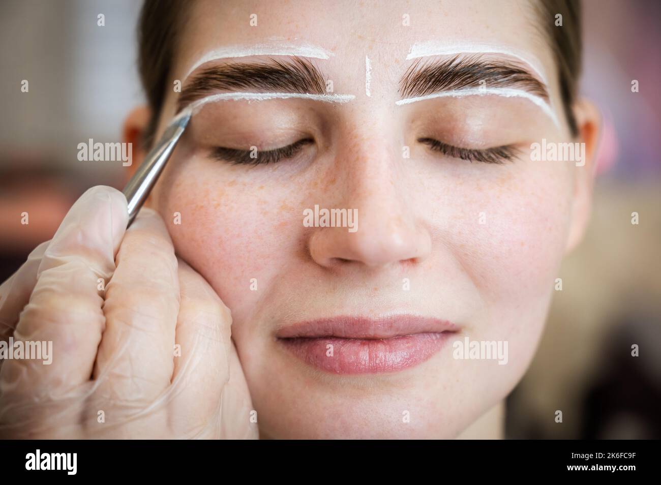 The master draws the shape of the eyebrows with white paint before ...