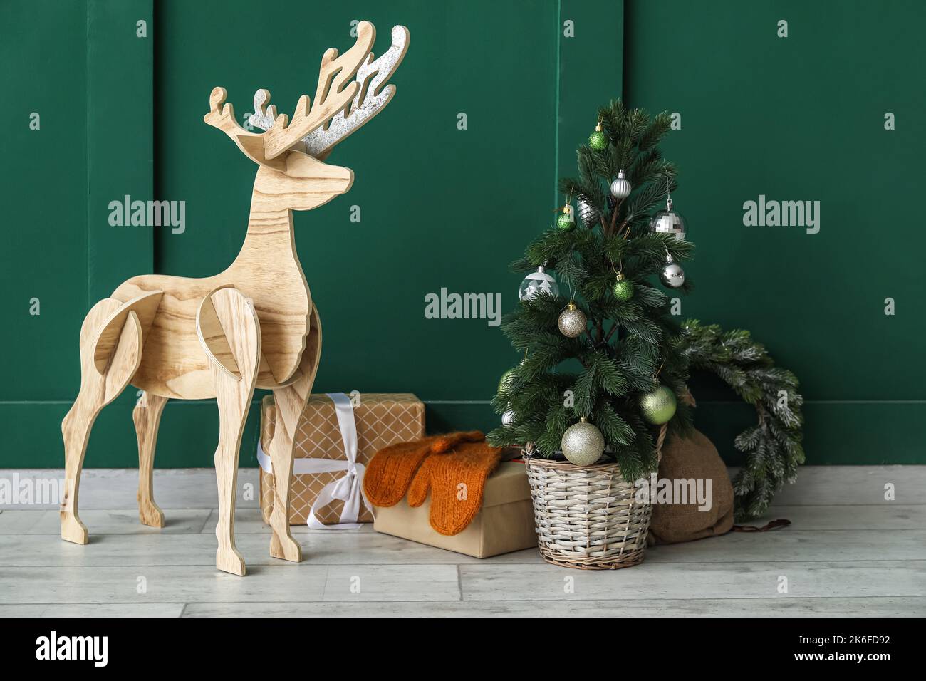 Wooden reindeer with Christmas tree and presents near green wall Stock ...