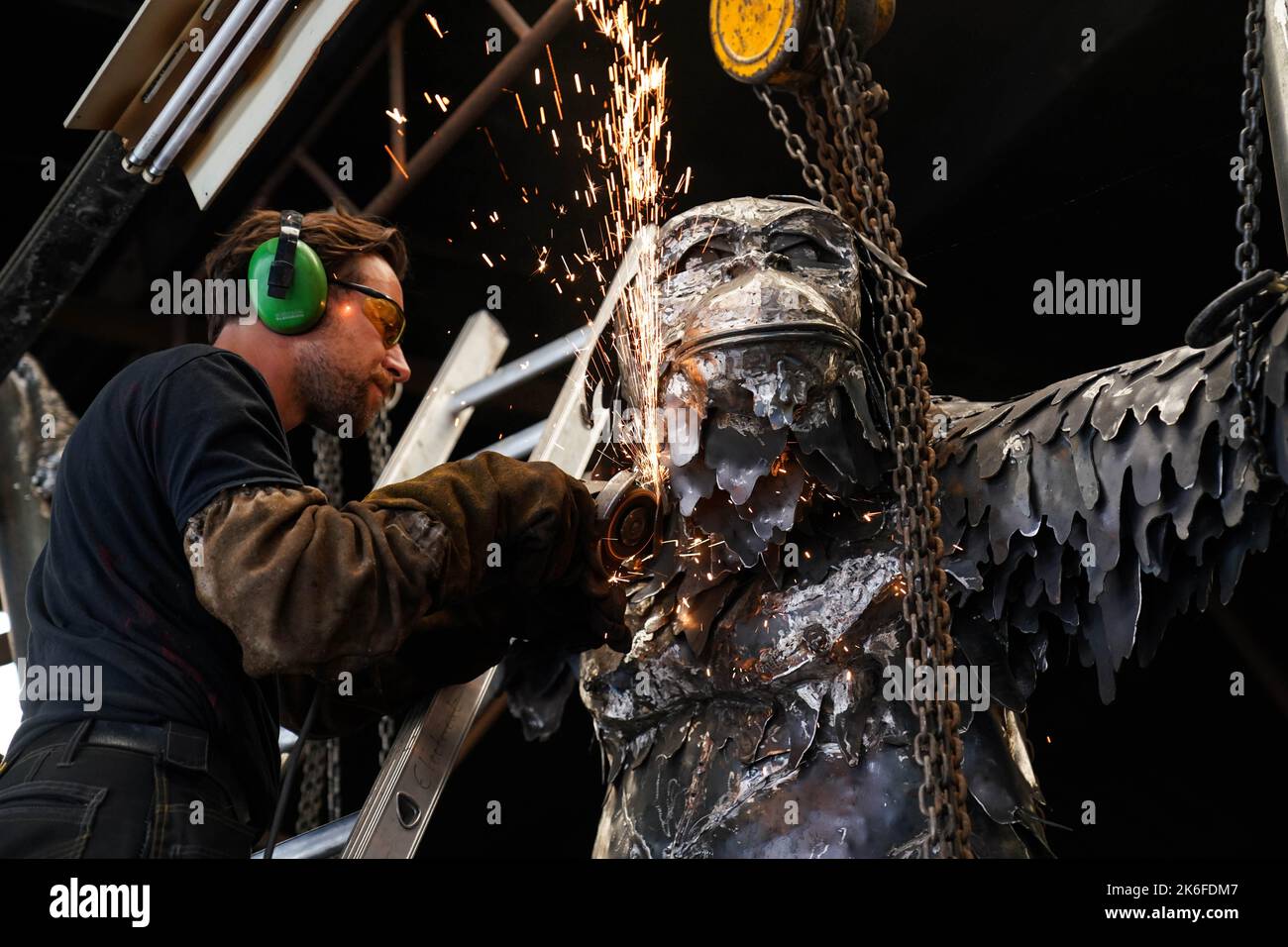 Sculptor Luke Perry applies finishing touches with an angle grinder to ...