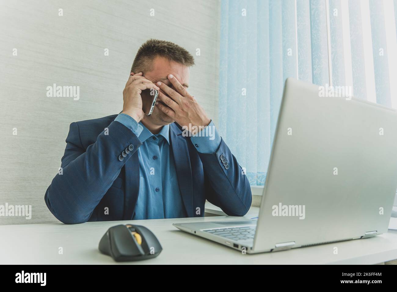 Thoughtful businessman talking on the phone. a tired employee at work ...