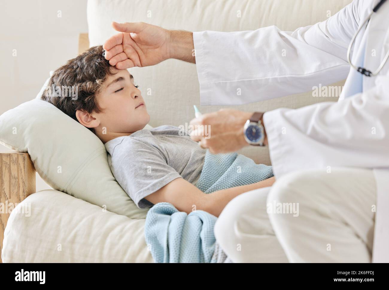 Hot to the touch. a male doctor taking a little boys temperature at ...