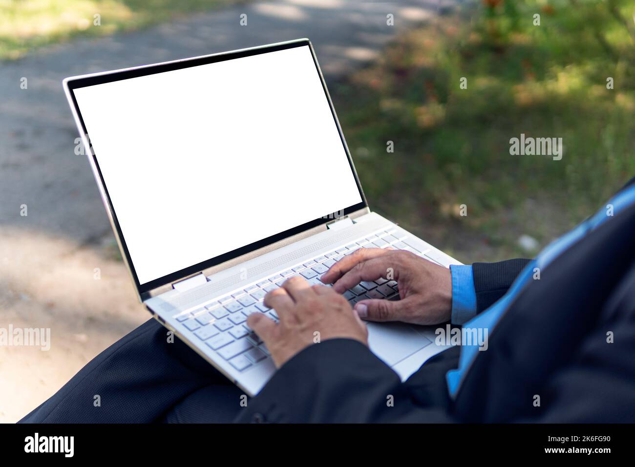 Young hipster student using laptop on grass in park at sunset. Blank ...