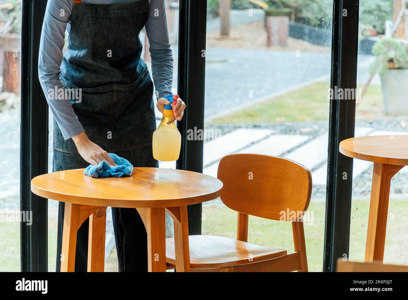 asian woman waitress staff in apron cleaning table with disinfectant ...