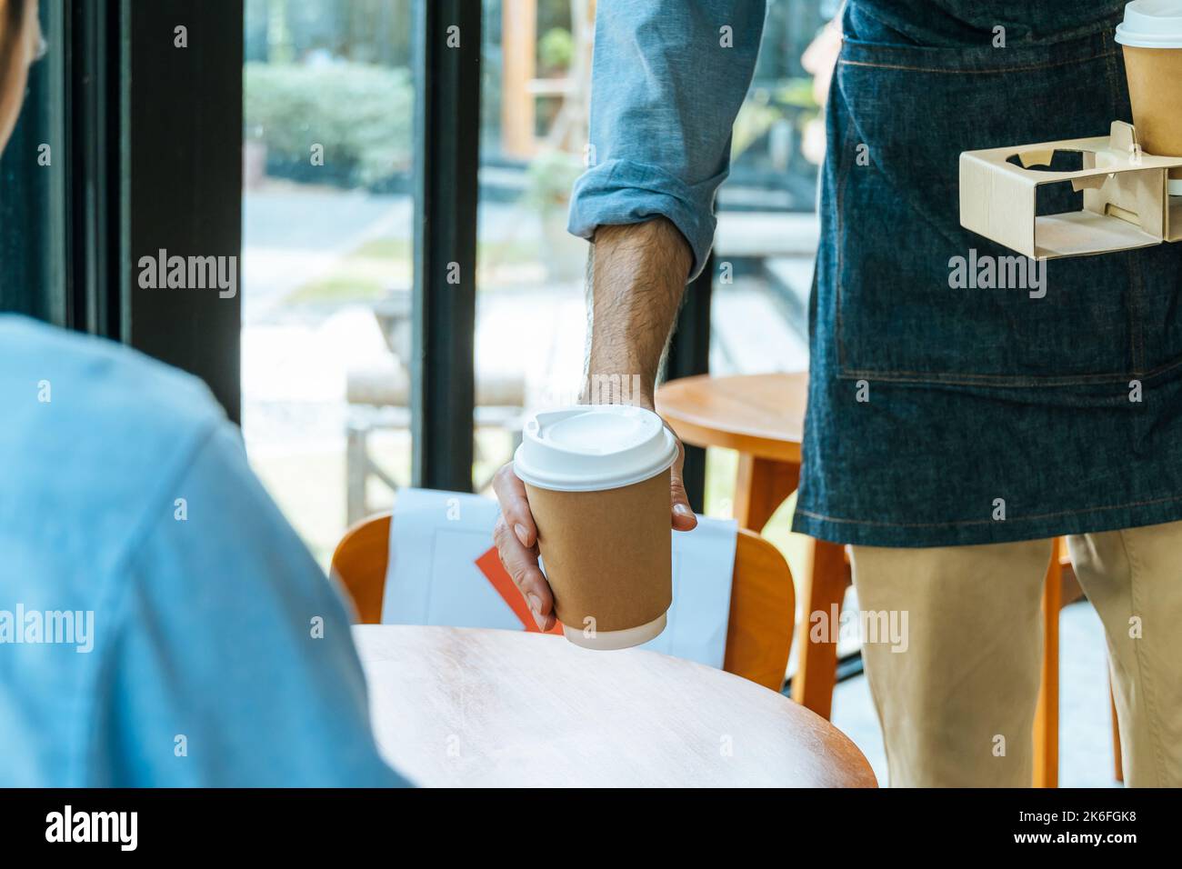asian staff wearing apron serving hot black coffee cup to customer on ...