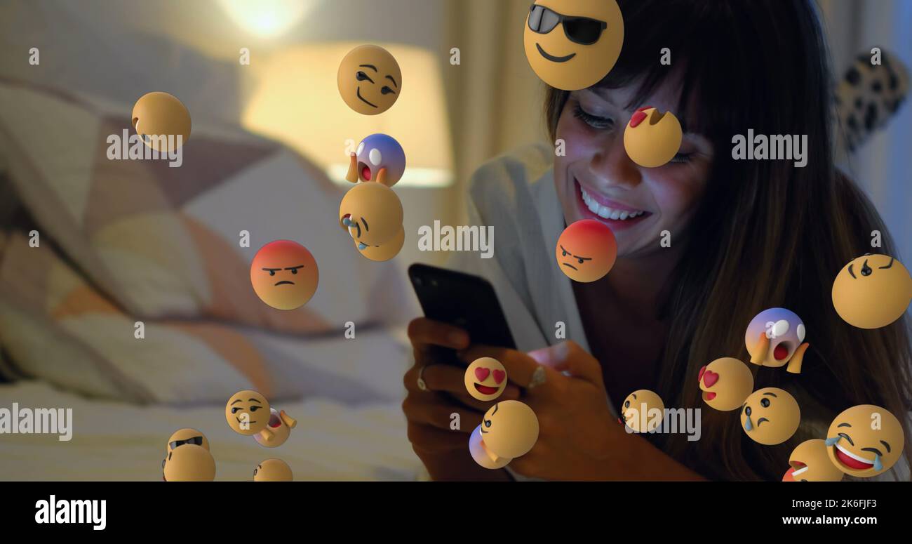 Image of emoticons over happy caucasian woman lying with smartphone in ...