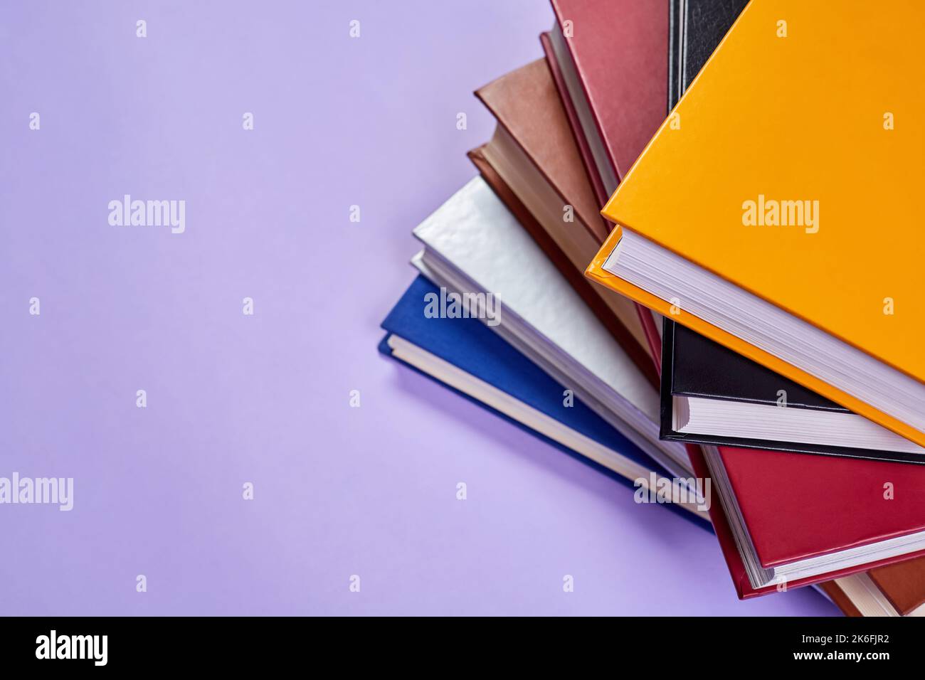 Stack of colorful books on purple background Stock Photo - Alamy