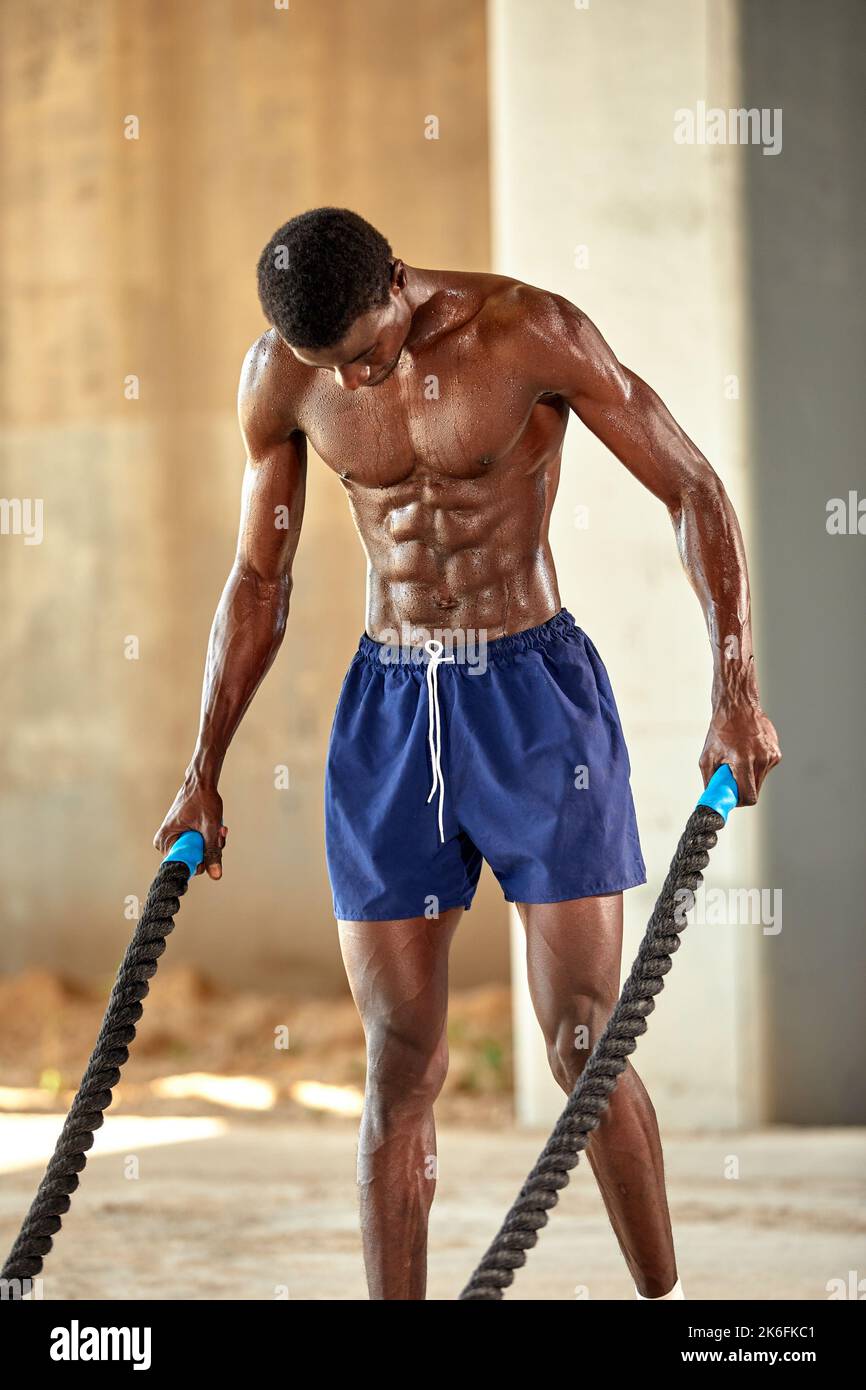 Rope workout. Sport man doing battle ropes exercise outdoor. Black male ...