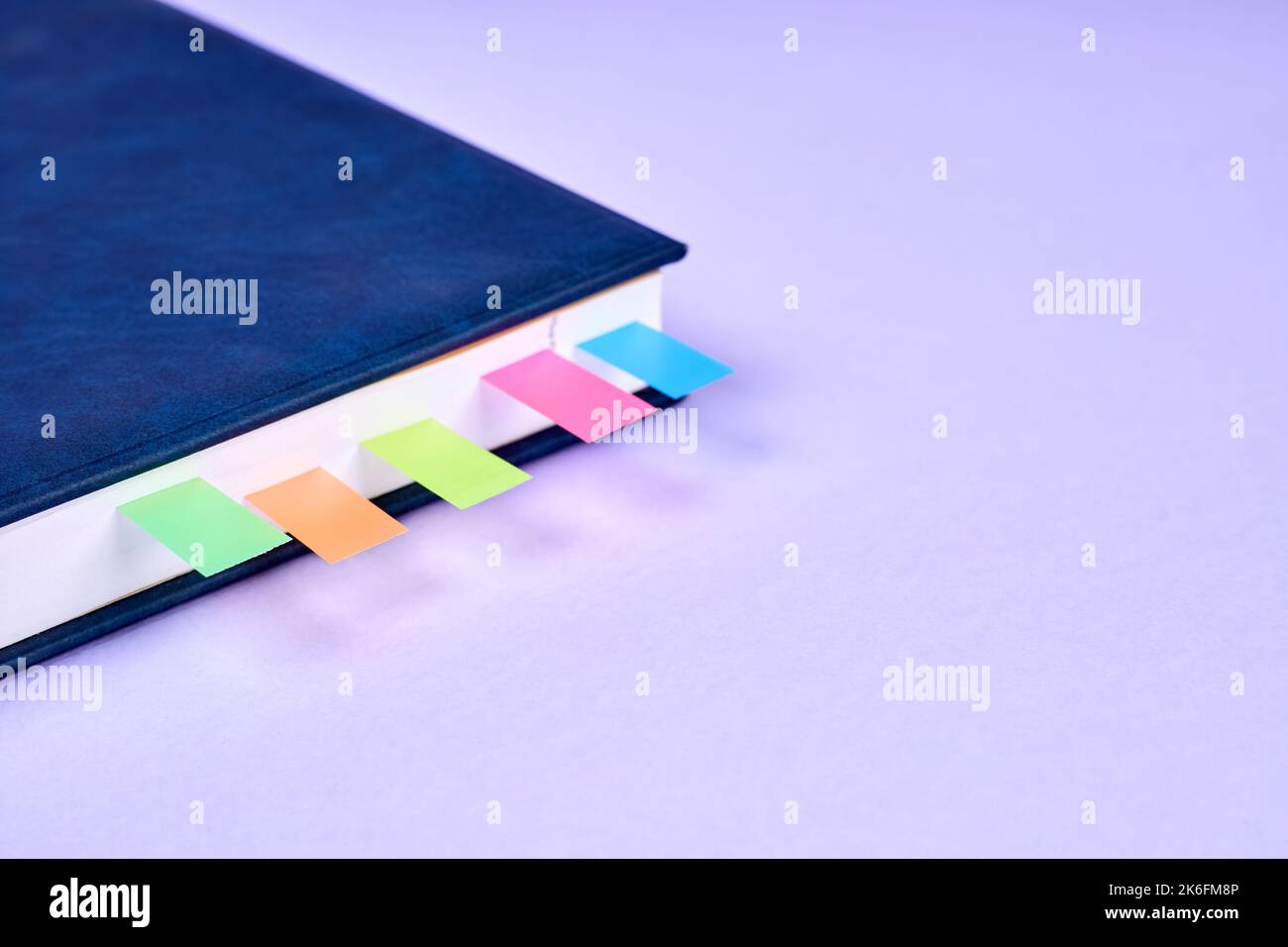 An office notepad with colorful sticky page markers sandwiched between ...