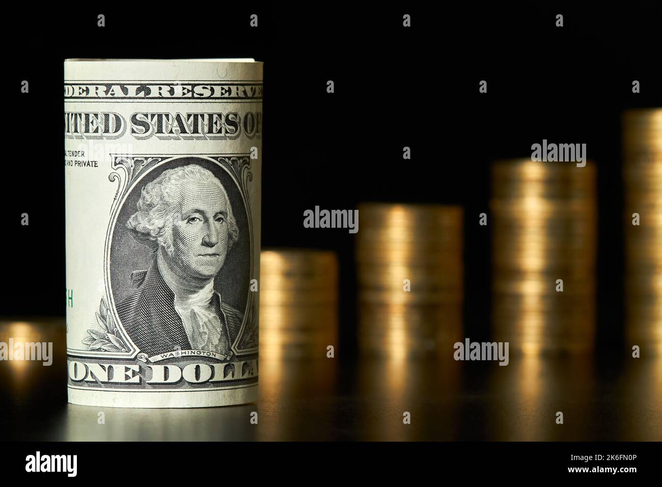 Rolled one dollar bill on the background of stacks of coins Stock Photo ...