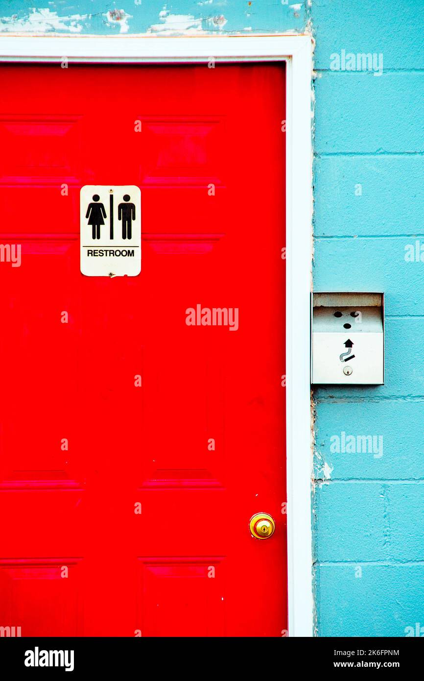 Male and female signs on red wooden restroom door of blue stone ...