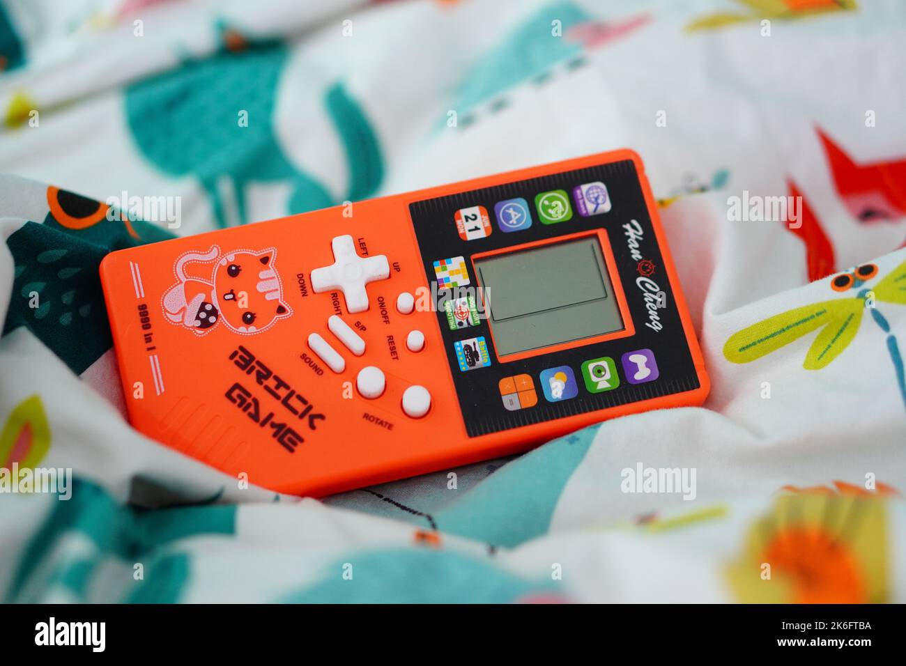 A closeup of a Han Cheng brand handheld console with brick games on a ...
