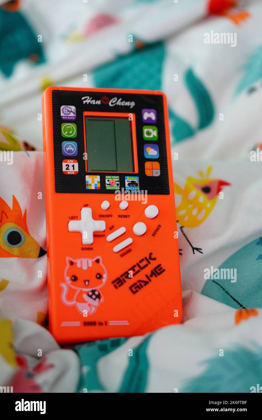 A vertical closeup of a Han Cheng brand handheld console with brick ...