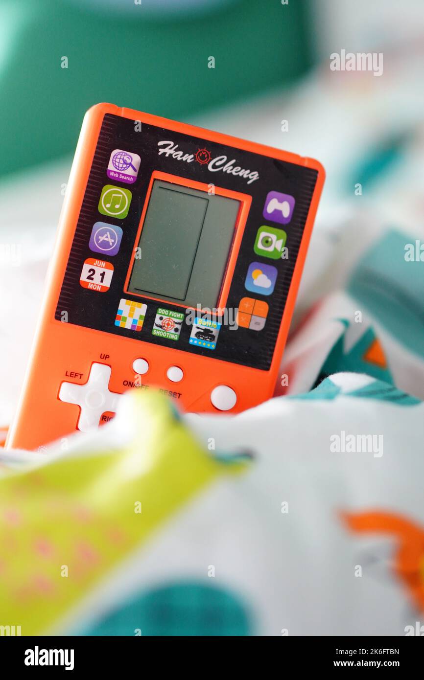 A vertical closeup of a Han Cheng brand handheld console with brick ...