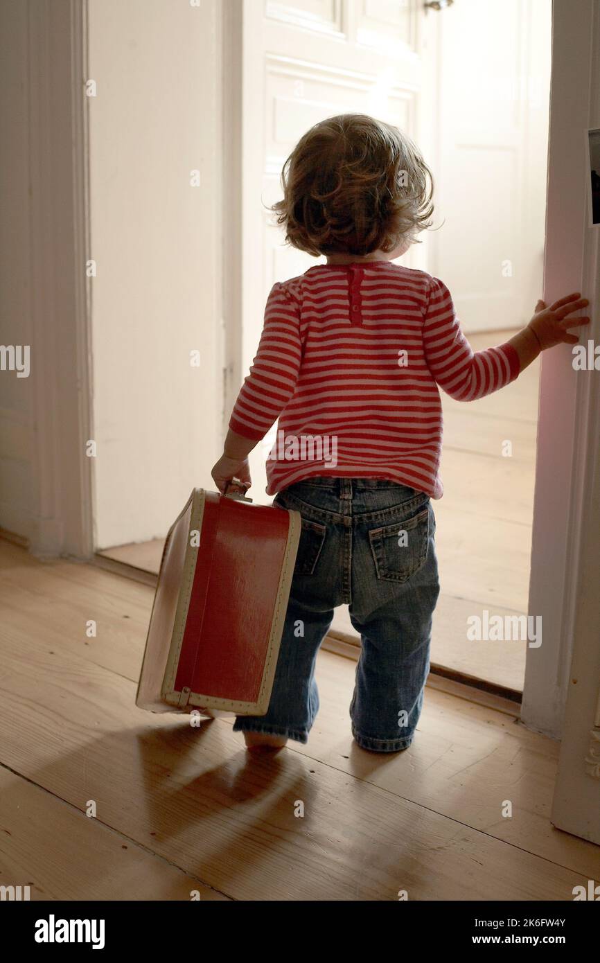 Toddler girl carrying small suitcase indoors Stock Photo - Alamy