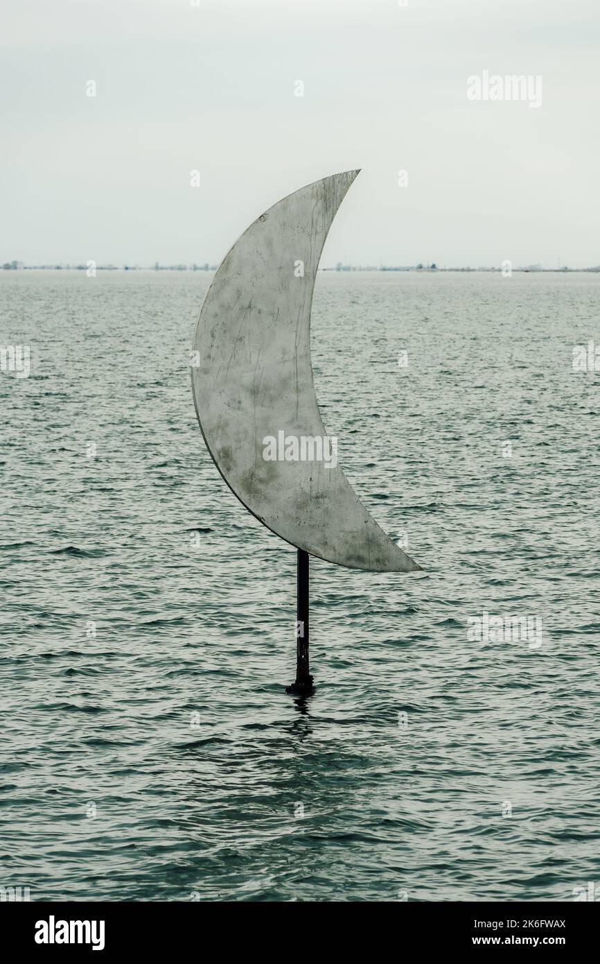 Day view of moon artwork installation above a calm sea level under hazy ...
