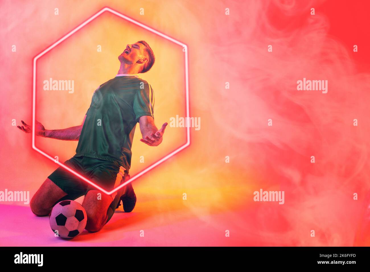 Caucasian male player with arms outstretched kneeling over glowing ...