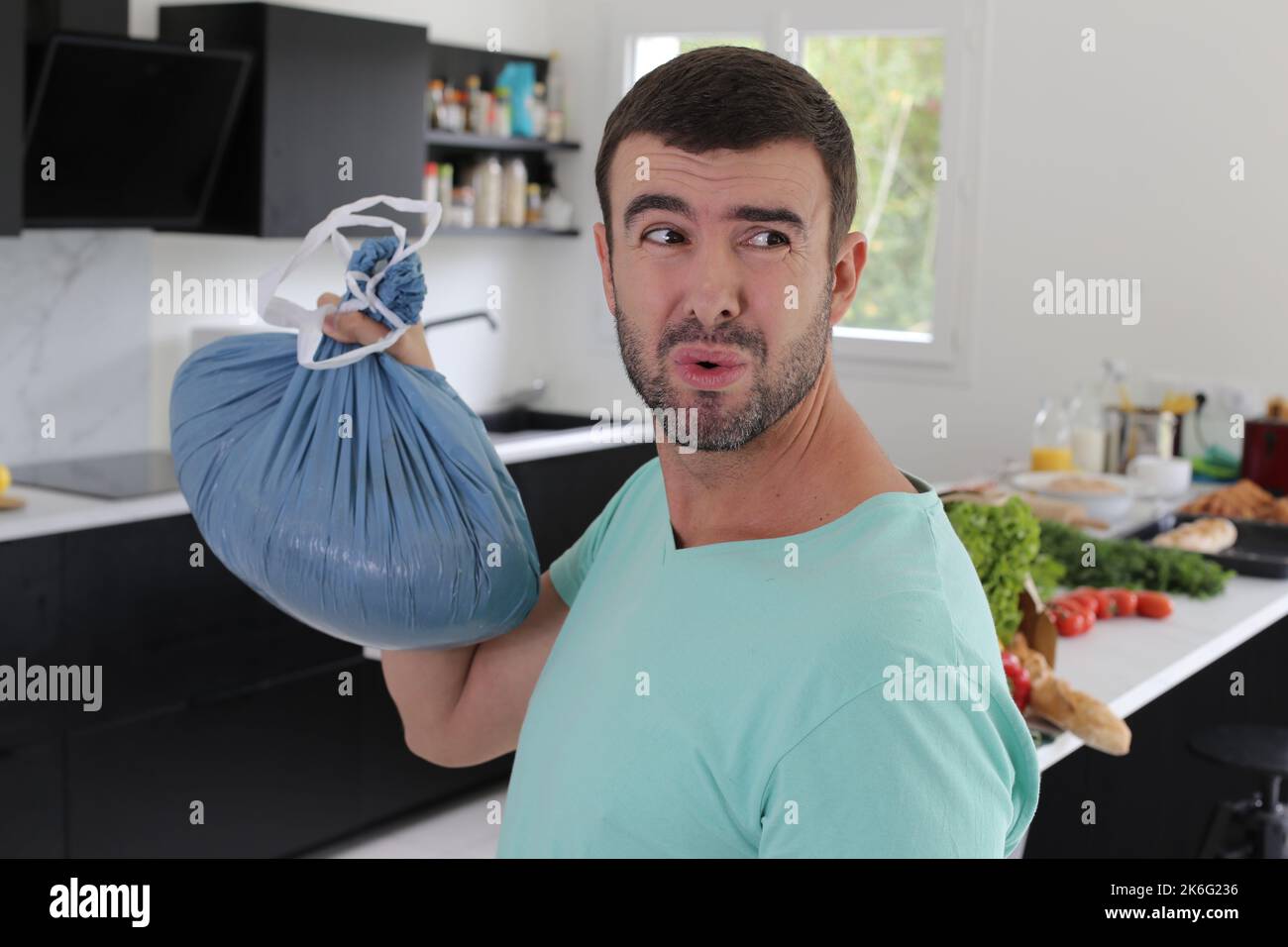Disgusted man holding stinky garbage bag Stock Photo - Alamy