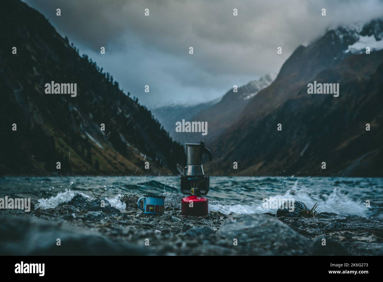 Bialetti Moka pot and mug on the lakeshore between mountains in bad ...