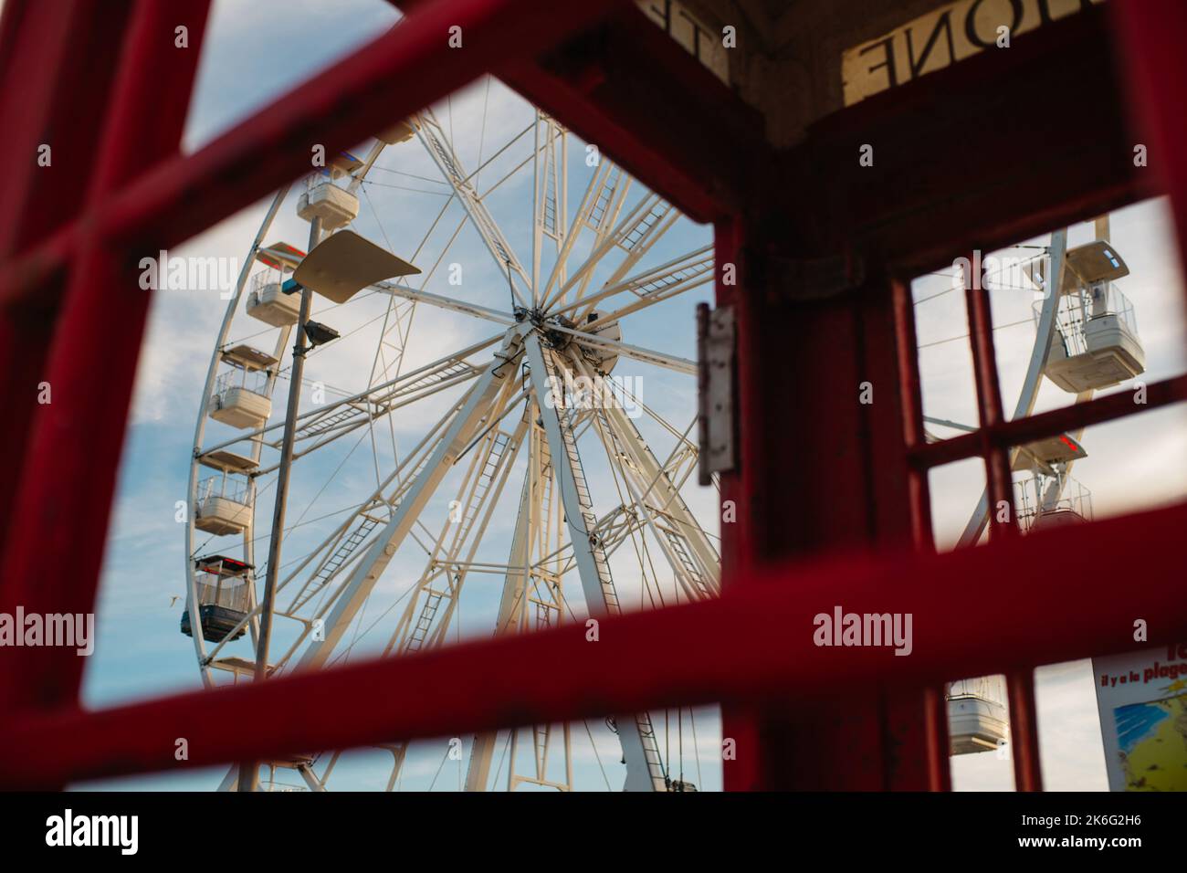 A low-angle view of the Ferris wheel through a British phone booth ...